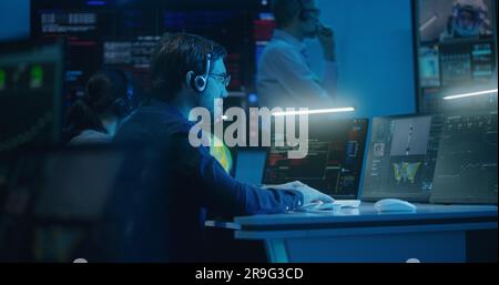 Diverse flight control operators in headsets monitor space mission on ...