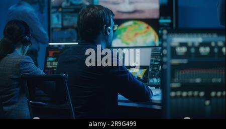Diverse flight control operators in headsets monitor space mission on ...