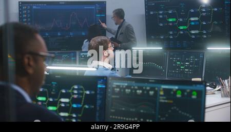 Technical support specialists sit at computers with displayed blockchain network map and server ...