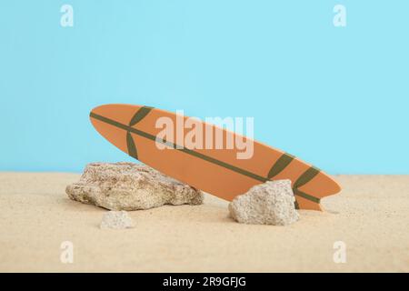 Mini surfboard with stones on sand against blue background Stock Photo ...
