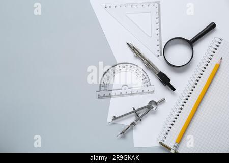 Different rulers, magnifying glass and compass on light grey background ...