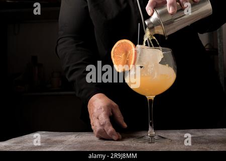 waitress dressed in black serving a banana cocktail with ice and a ...