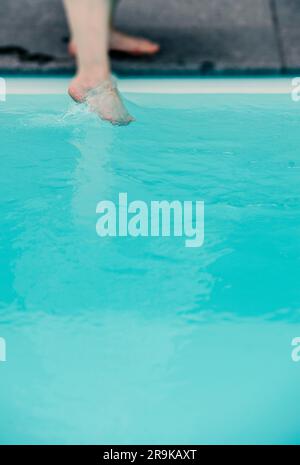Woman dipping toes into swimming pool Stock Photo - Alamy