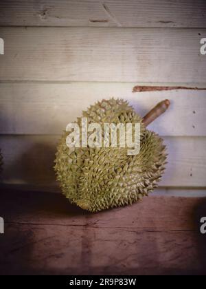 Yellow durian fruit cut open in a rattan basket on an old wooden ...