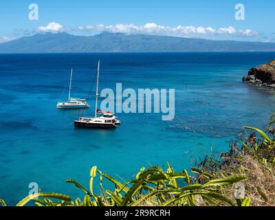 Boats are anchored in a shallow cove that is perfect for snorkeling ...