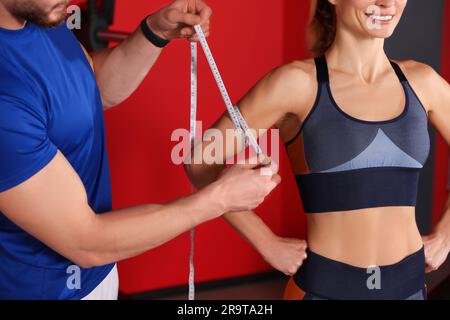 Trainer measuring woman`s triceps with tape in gym, closeup Stock Photo ...