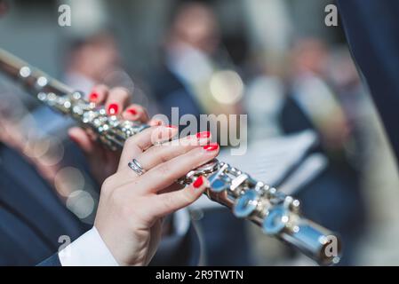 Woman's hands playing a transverse flute with sheet music in the ...