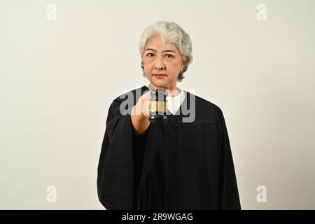 Strict senior female judge dressed in robe gown uniform with gavel ...