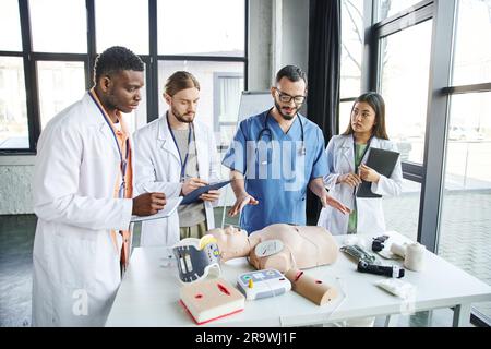 multicultural students in white coats looking at professional paramedic ...