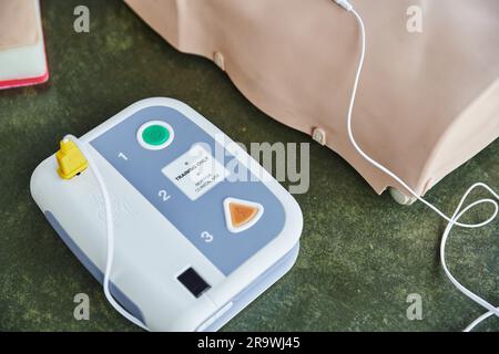 high angle view of CPR manikin near wound care simulator and automated external defibrillator on ...