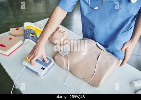 high angle view of CPR manikin near wound care simulator and automated external defibrillator on ...