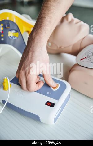 cardiac resuscitation skills, healthcare worker applying defibrillator pads on CPR manikin near ...
