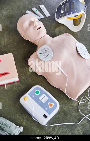 high angle view of CPR manikin near wound care simulator and automated external defibrillator on ...
