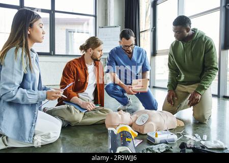 professional paramedic showing wound care simulator to diverse group of ...