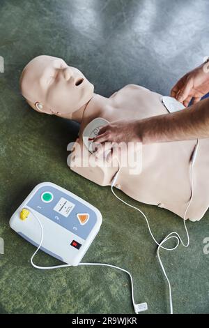 high angle view of CPR manikin near wound care simulator and automated external defibrillator on ...
