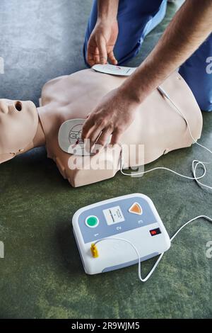 high angle view of CPR manikin near wound care simulator and automated external defibrillator on ...