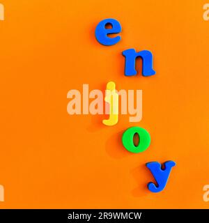 Colourful letters form the word enjoy, vertical arrangement, tabletop ...