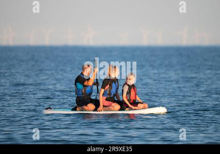 Adult male with 2 younger females (possibly a family) on a paddleboard ...