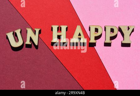 Unhappy in wooden letters with the prefix UN crossed out, leaving the ...
