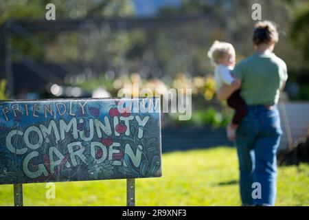 community garden sign at a vegetable garden with a mother and baby in a ...