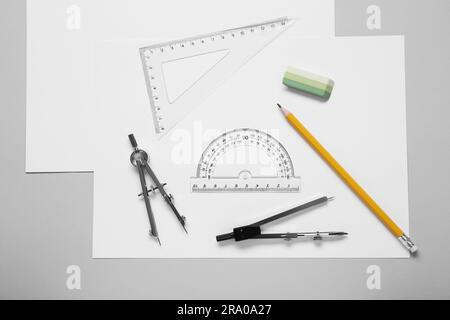 Different rulers and compasses on light grey background, flat lay ...