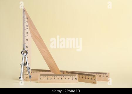 Different rulers and compass on yellow background, flat lay. Space for ...