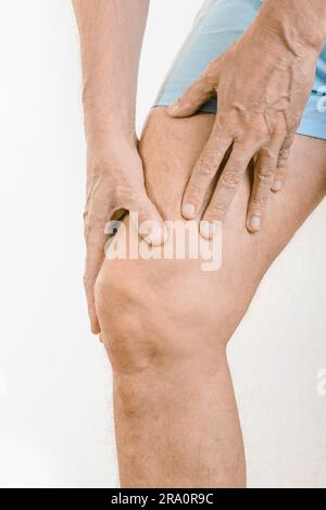 Athlete man massaging a painful quadriceps and the knee after a sport ...