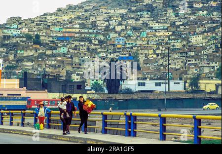 Peru, Lima; Women going to a party. In the background one of the slums ...