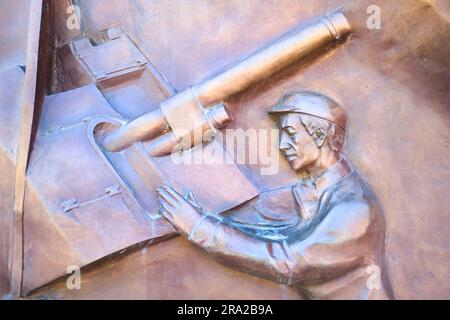 A factory worker building an artillery gun. Detail of the front entrance bronze frieze. At the ...