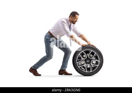 Man pushing a spare car tire towards a SUV isolated on white background ...