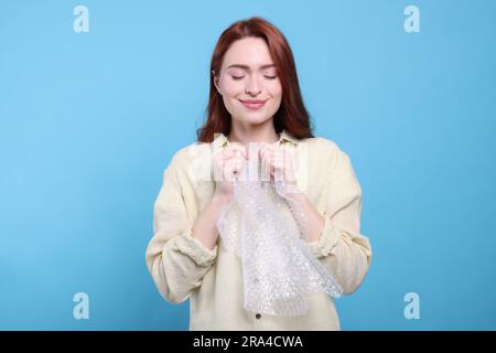Woman popping bubble wrap on beige background, closeup. Stress relief ...