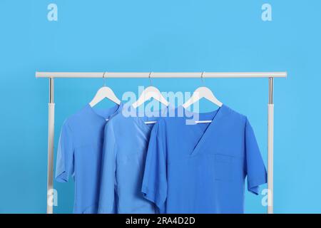 Medical uniforms on rack against light blue background Stock Photo - Alamy