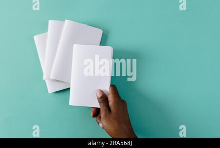 Hand of biracial man holding notebook over notebooks with copy space on ...
