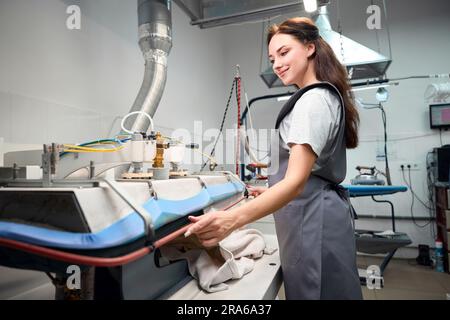 Laundry office worker drying and ironing clothes using steam press ...
