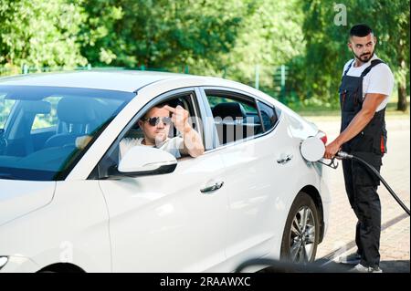 Smiling petrol pump worker showing green screen empty card by looking ...