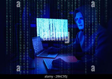 Anonymous man in mask with computers and binary code in darkness Stock ...