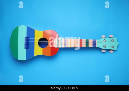 Colorful ukulele on light blue background, top view. String musical ...
