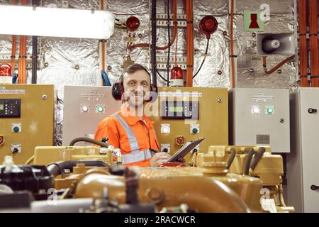 Young marine engineer making notes in engine room log book. Offshore ...