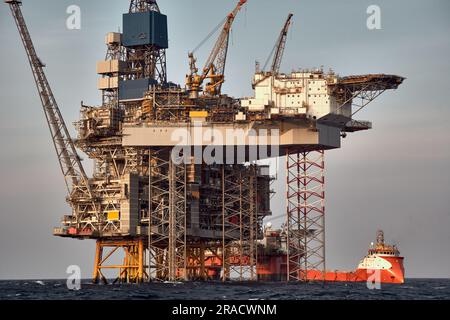 Close up of jack up oil and gas offshore platform with supply vessel ...
