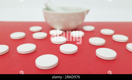 Effervescent tablets and mortar in red background Stock Photo - Alamy