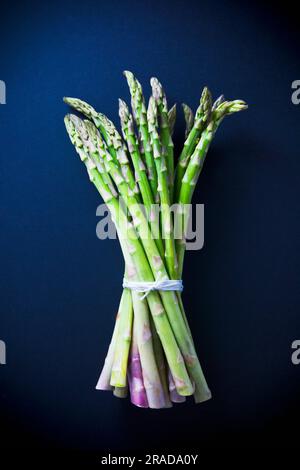 Bundle of green asparagus on black background and light effect. Close ...