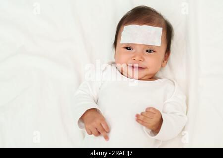 happy sick baby with cool fever jel pad on forehead Stock Photo - Alamy