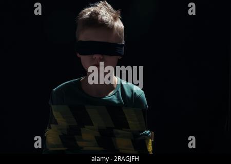 Blindfolded little boy tied up and taken hostage against dark ...