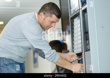 man getting drink from vending machine Stock Photo - Alamy