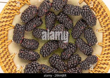 Several sweet blackberry berries with ceramic plate and wooden spoon on ...