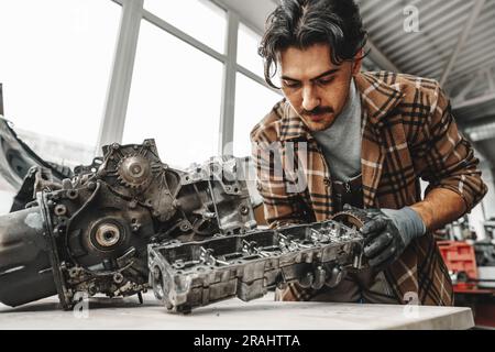 Workman disassembling car engine at the working table of the car ...
