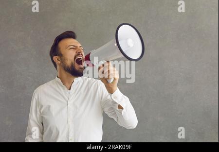 Young caucasian man over grey grunge wall holding hard drive with angry ...