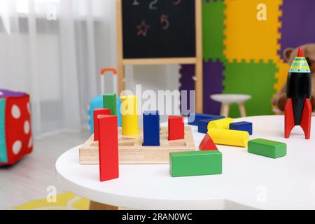 Different toys on white table and chairs in playroom. Kindergarten ...