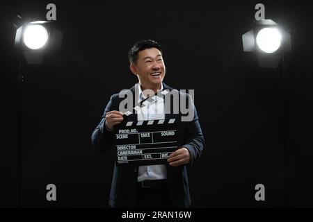 Happy asian actor with clapperboard on light blue background. Film ...