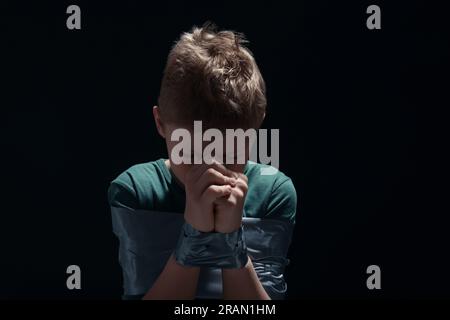 Victim boy with hands tied up with rope in emotional stress and pain ...
